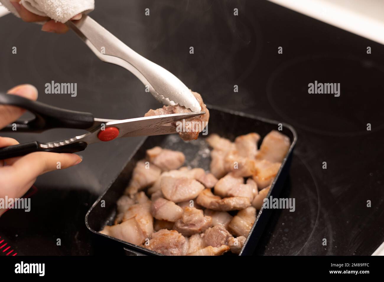 Cut the meat with scissor, cooking pork belly meat with frying pan and ...