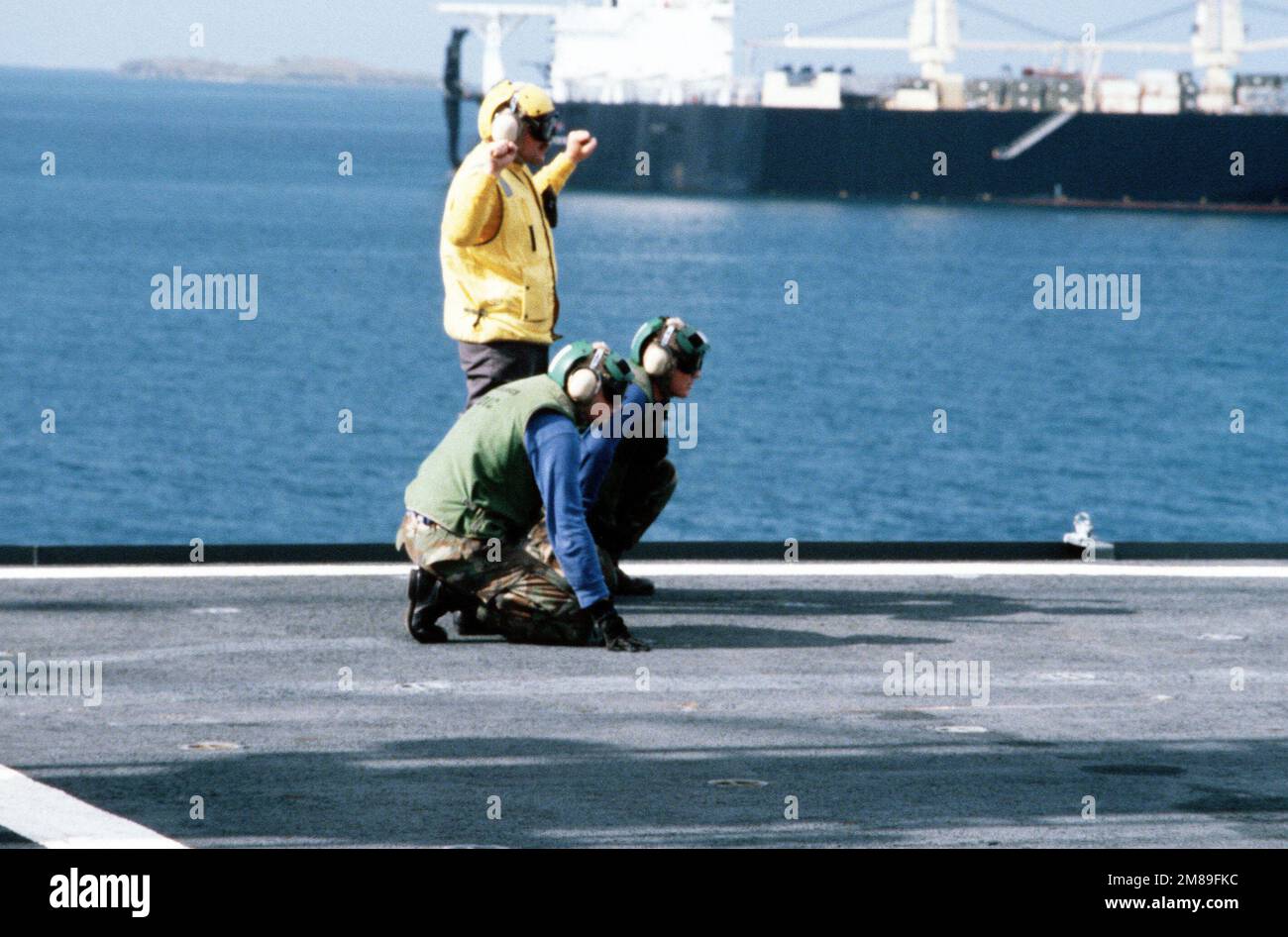 Two Marine flight deck crewmen stand by as the plane director aboard ...