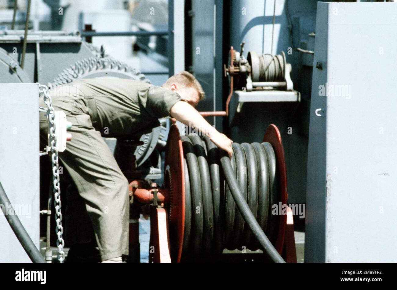 A Marine stows a fire hose aboard the aviation logistic ship USNS ...