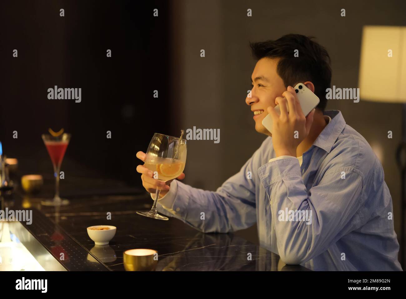 happy cheerful Asian young man on phone call at night bar. side view ...