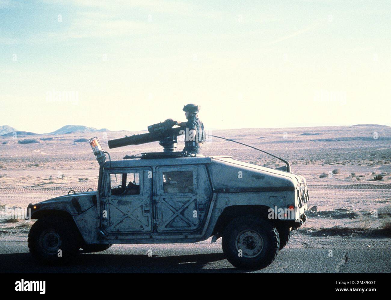 A soldier scans the horizon from an M-998 multipurpose wheeled vehicle ...