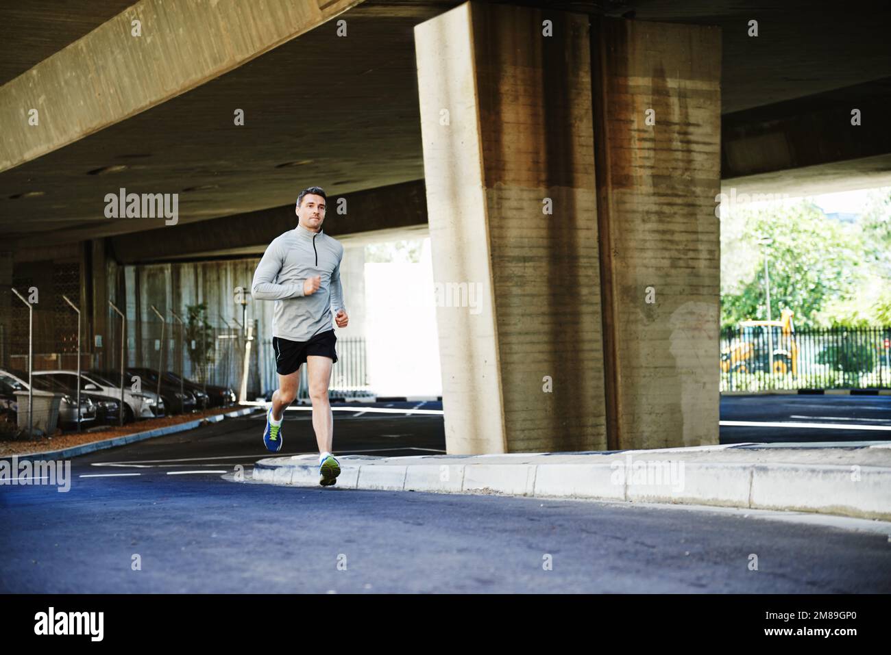 Working up a sweat. Young man keeping fit by going for a run in the ...