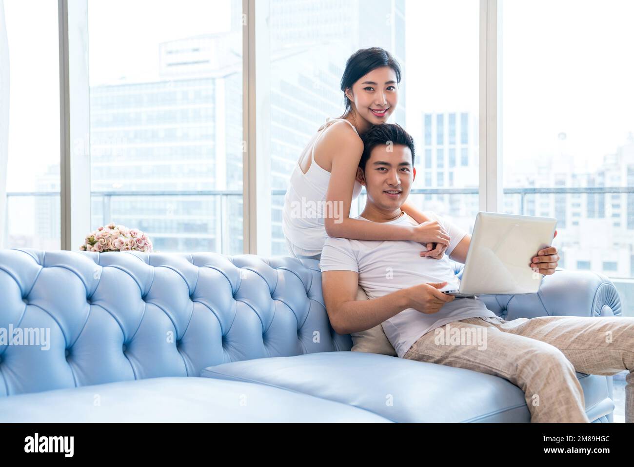 Young couples to use a computer on the sofa Stock Photo - Alamy