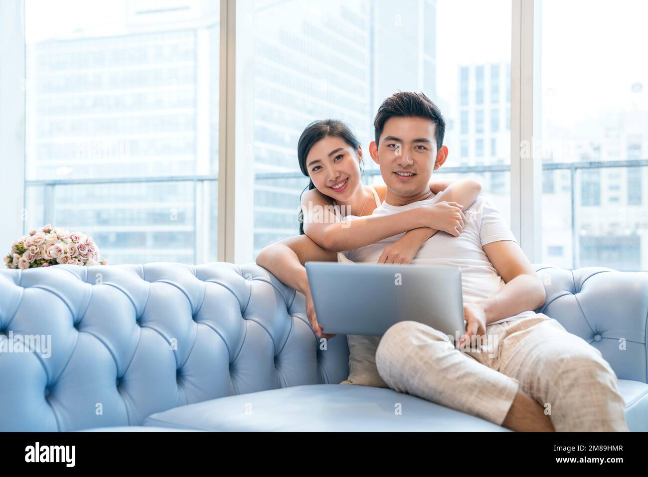 Young couples to use a computer on the sofa Stock Photo - Alamy