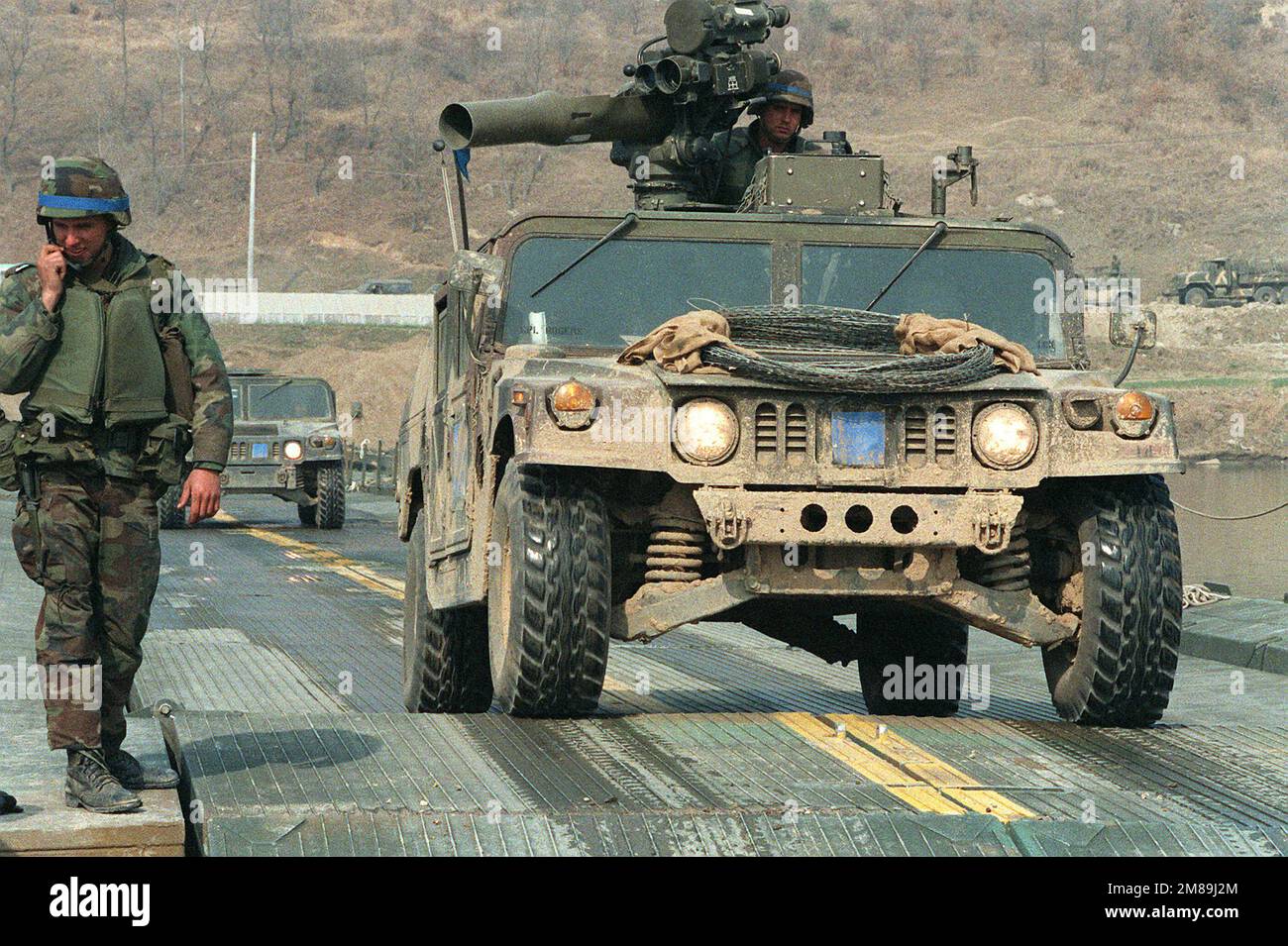 A combat engineer posted at the end of a ribbon bridge talks on a radio ...