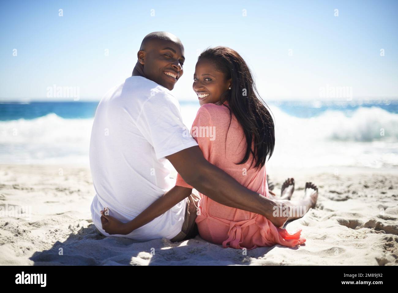 Intimacy on the beach. A happy african-american couple glancing over ...