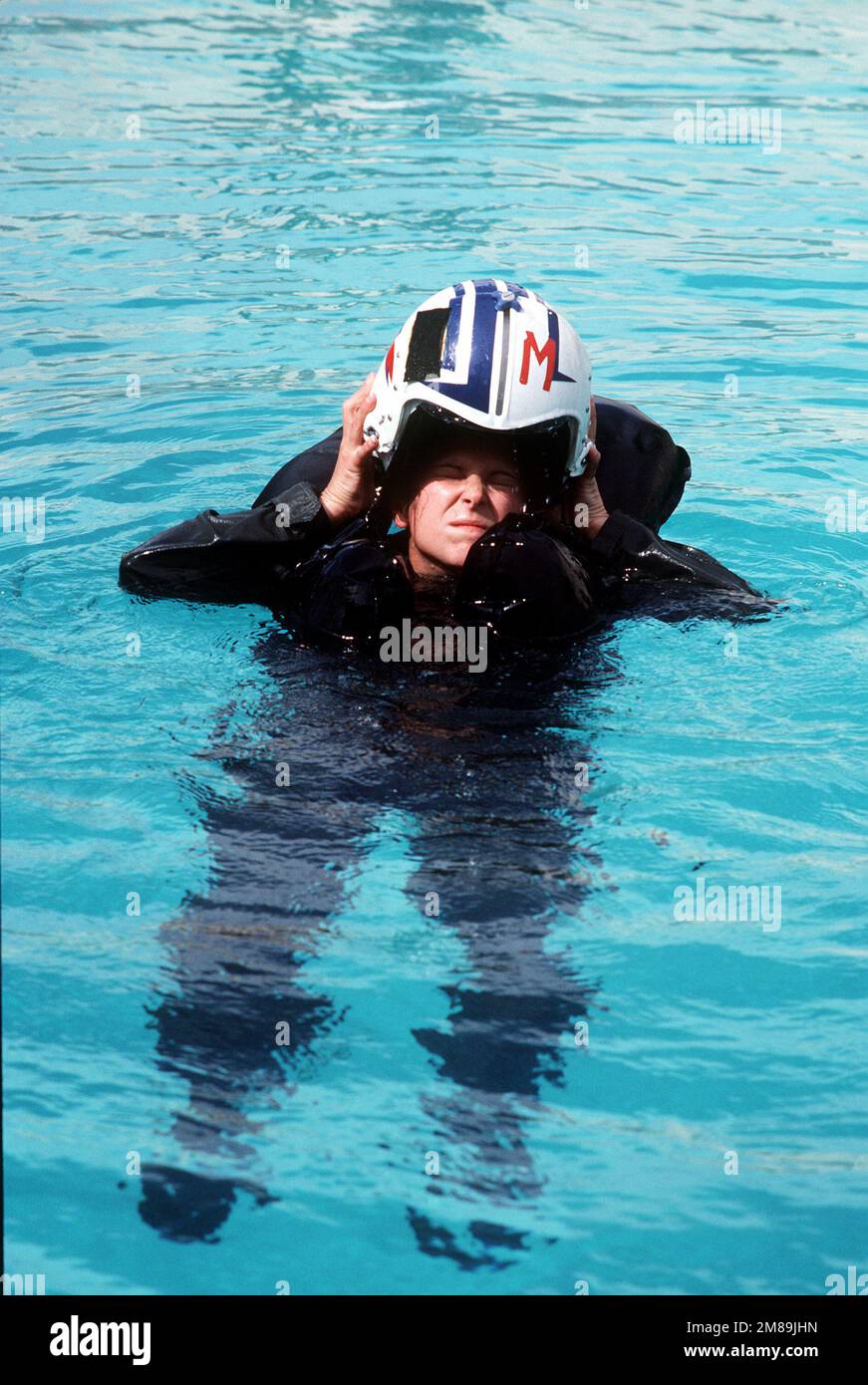 A female Navy pilot in flight gear practices s survival techniques ...