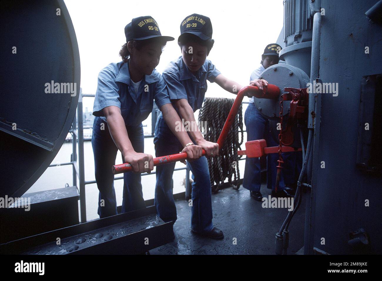 Two female crew members turn a hand crank aboard the submarine tender ...