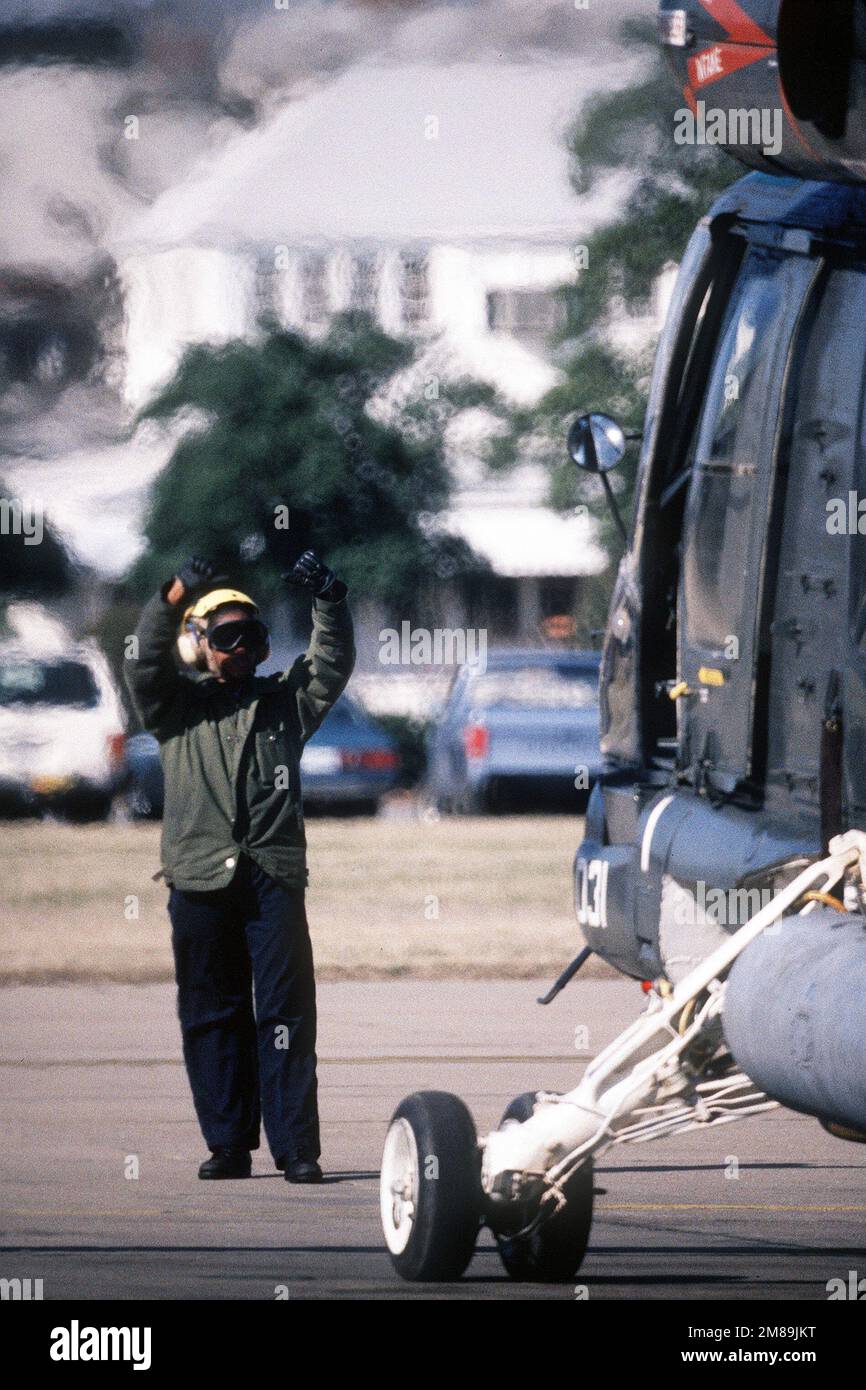 A female Navy ground crewman directs an SH-2F Sea Sprite helicopter on ...