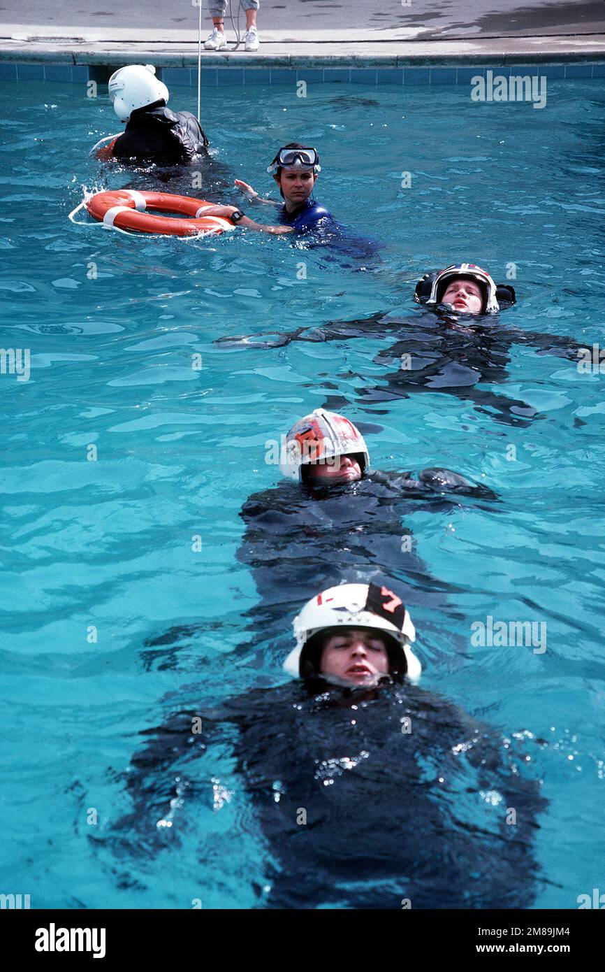 Male and female Navy pilots in flight gear tread water in a pool during ...