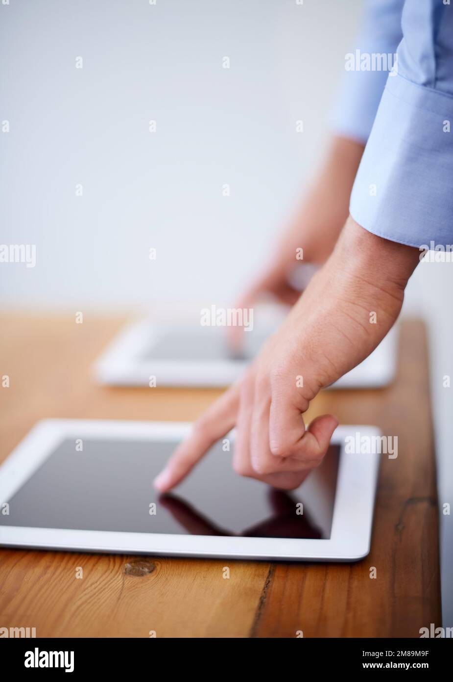 Syncing tablets. Cropped image of a businessman syncing two digital ... Syncing tablets. Cropped image of a businessman syncing two digital ...