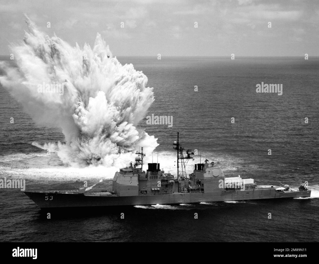 An explosion sprays water high above the guided missile cruiser USS ...