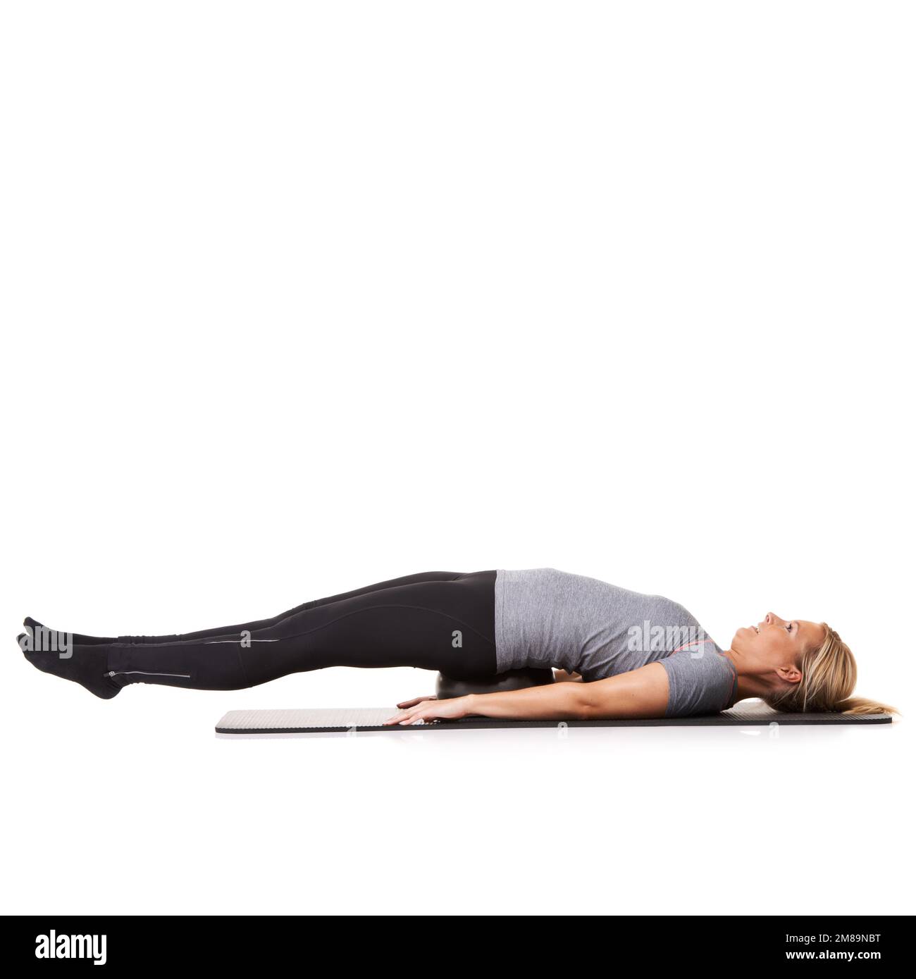 Feeling her muscles pull. A young woman lying on an exercise ball and ...