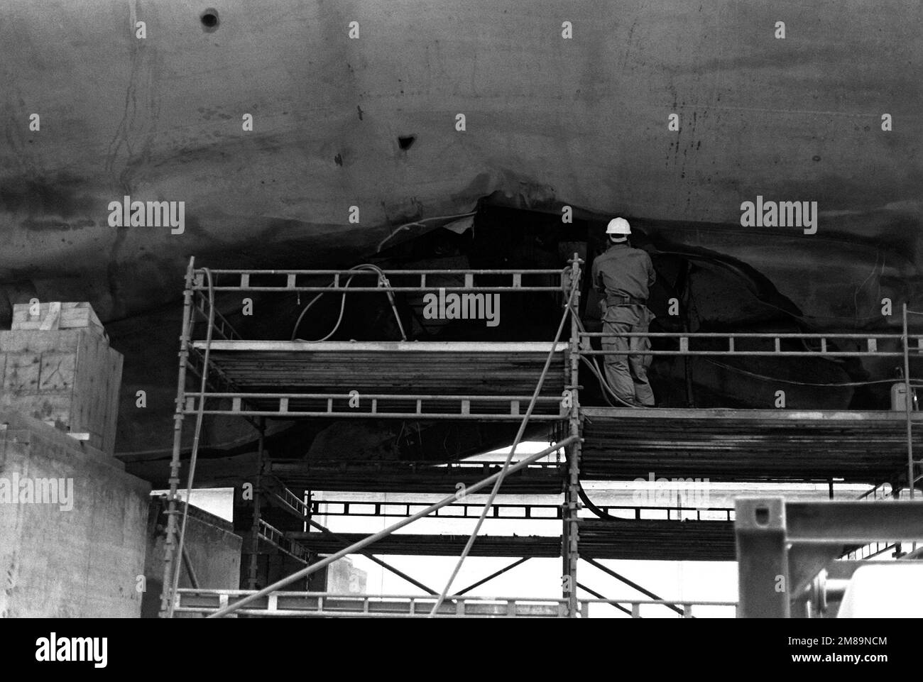 A photographer records the damage to the hull of the guided missile ...