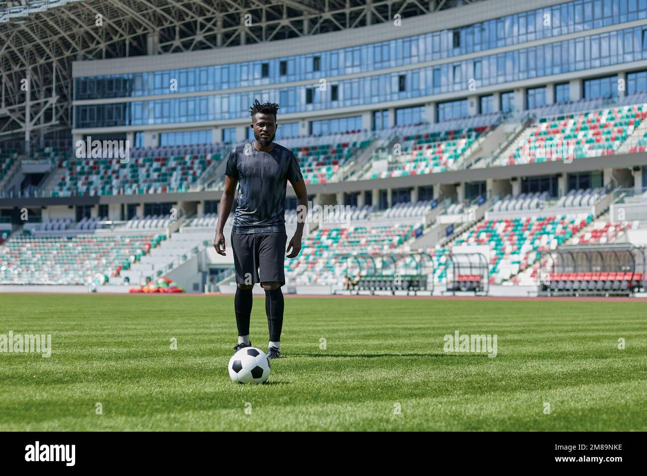 African American man playing football on the stadium field. A man runs ...
