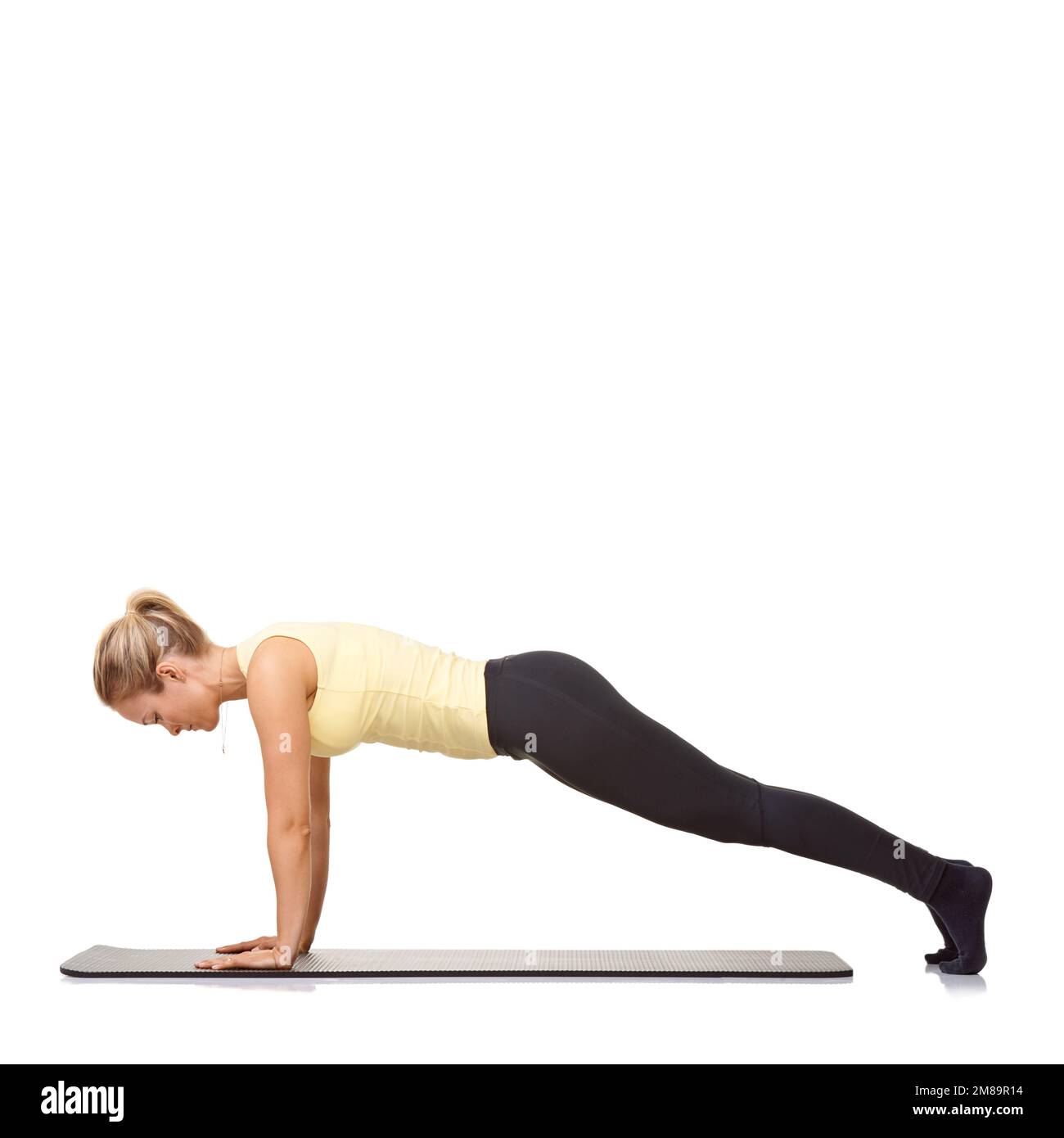 Working out. A fit young woman doing push-ups on her exercise mat while ...