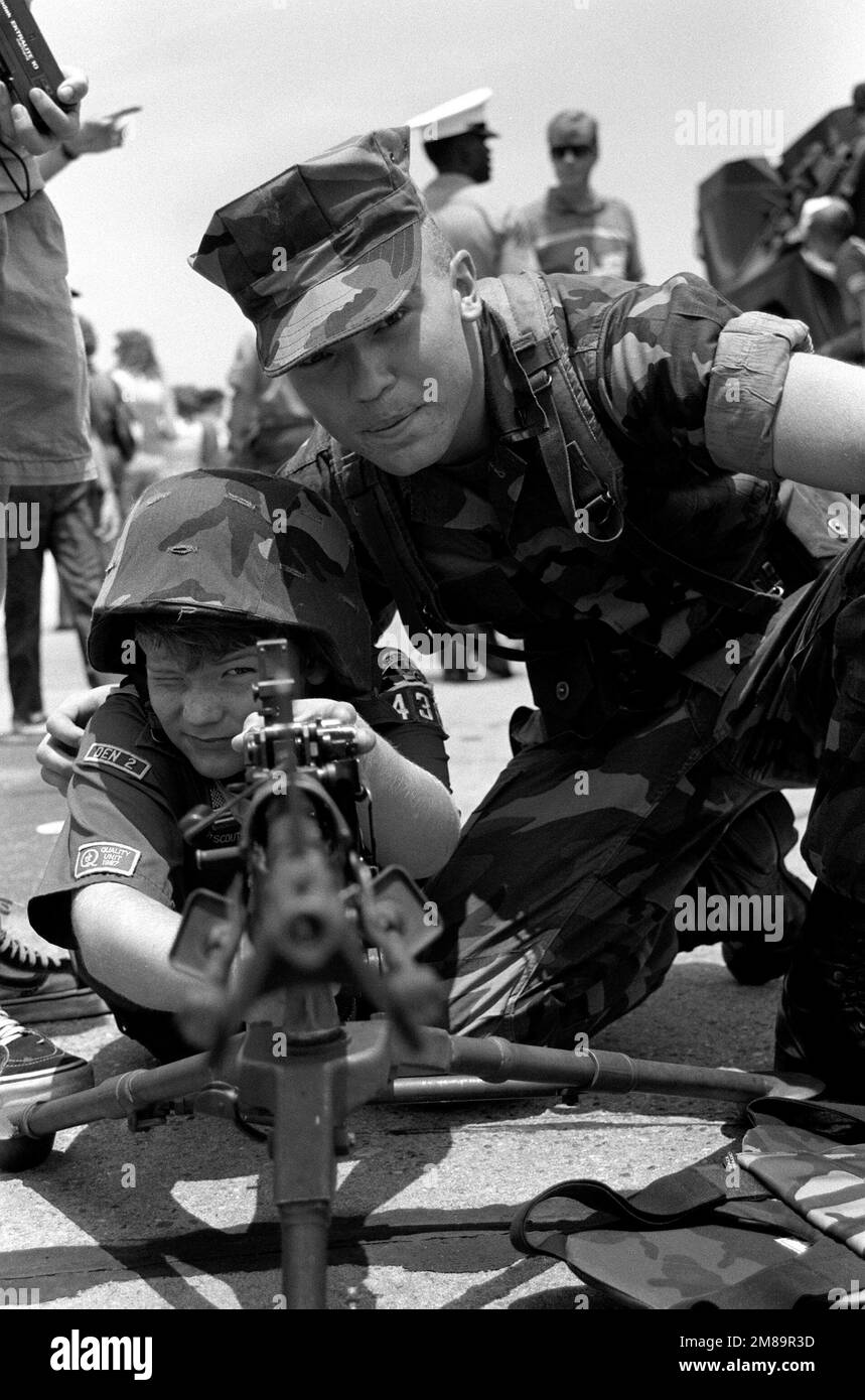 A Marine demonstrates use of a M-60 machine gun to a youngster ...