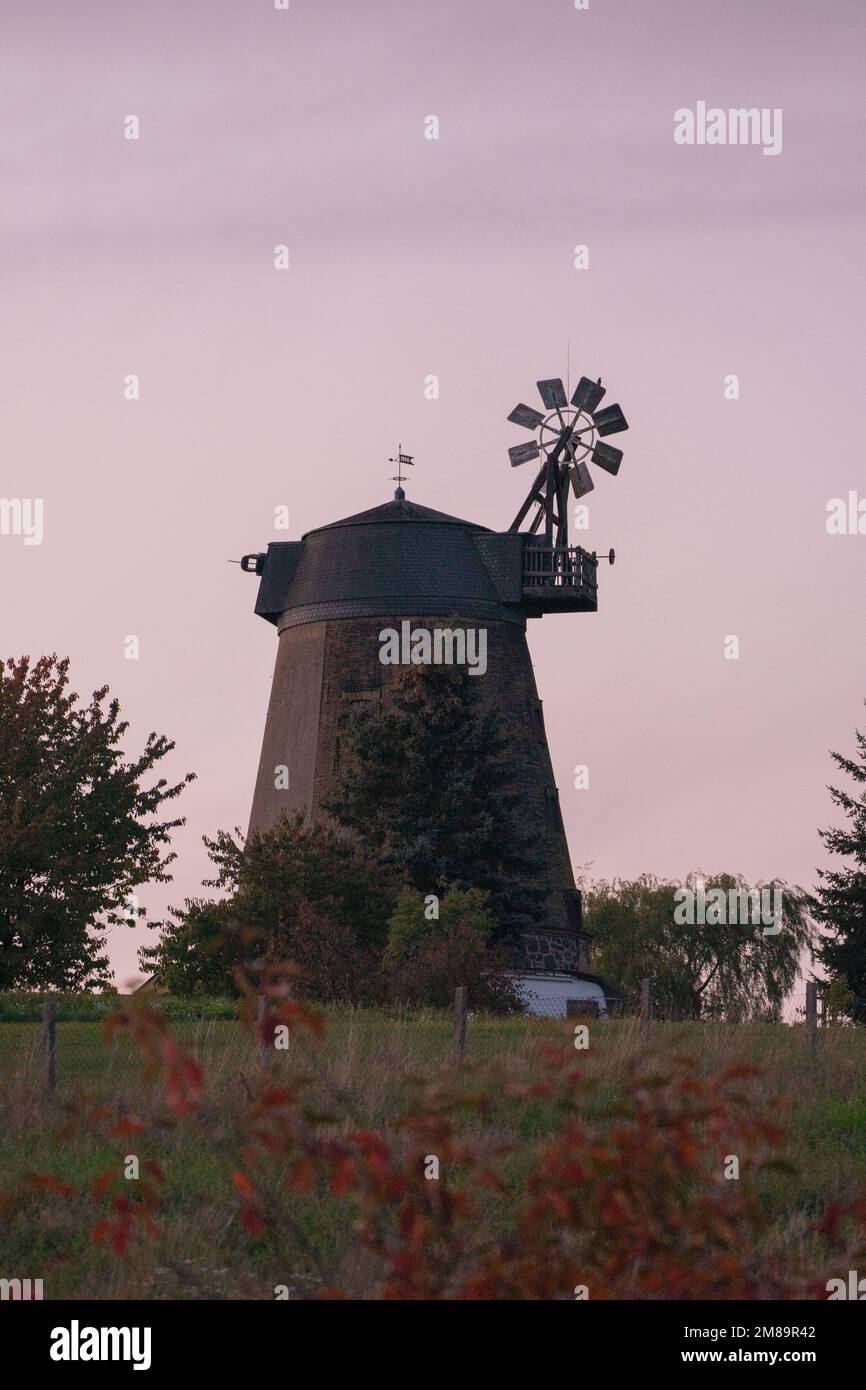 A vertical shot of an old windmill in a field in the countryside at ...