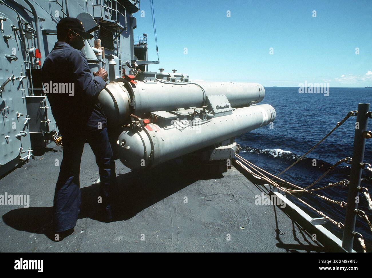 A crewman closes the breach of a Mark 32 12.75-inch torpedo launcher ...