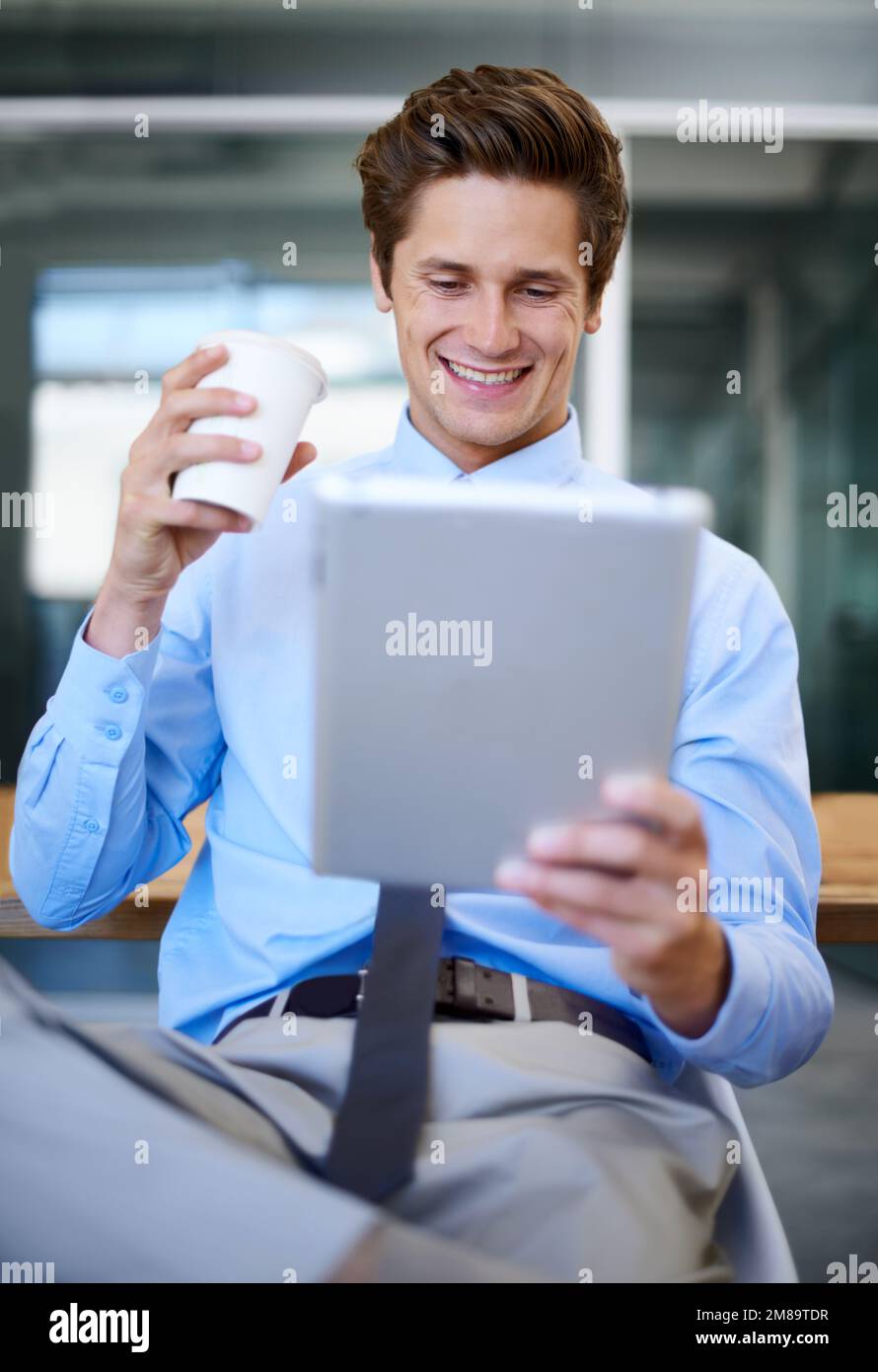 A well-deserved coffee break. A young businessman using his tablet ...