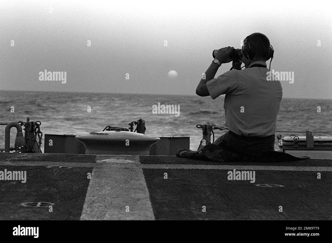 SEAMAN John Stengel, after lookout, uses binoculars to scan the horizon ...