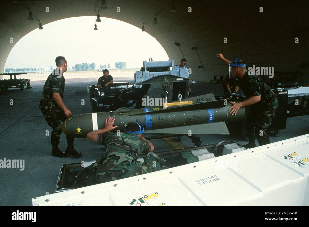 Airmen place an inert AGM-65 Maverick air-to-air missile on a cart with ...