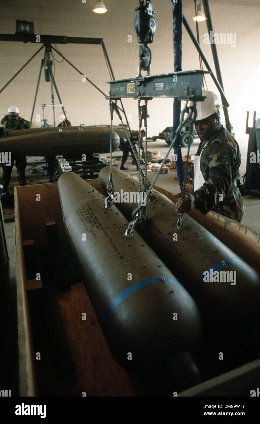 An airman guides a pair of CBU-58 cluster bombs as they are lifted out ...