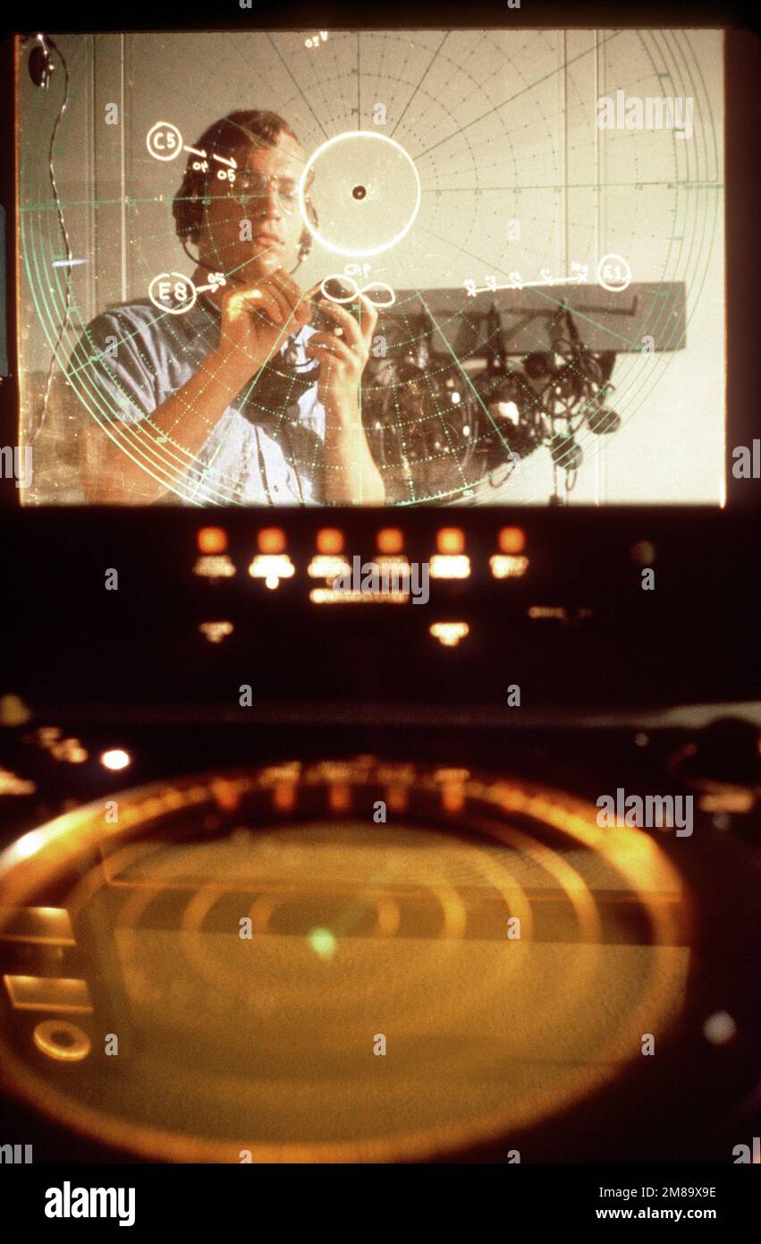 A crewmen marks a plotting board in a shipboard combat information ...