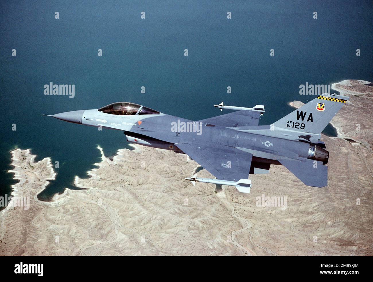An air-to-air left side view of an F-16C Fighting Falcon aircraft armed ...