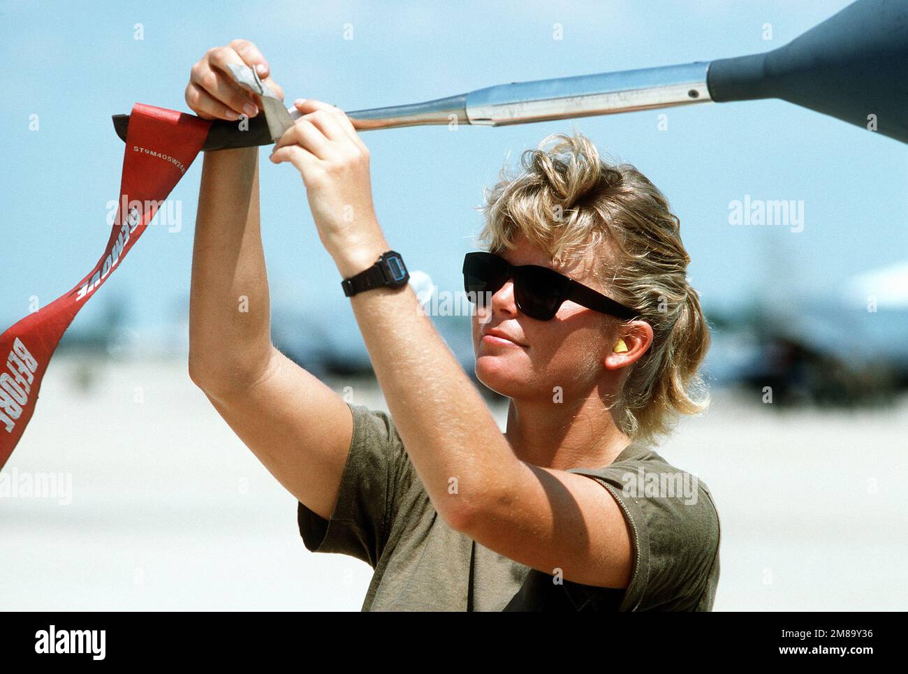 A USAF female crew chief places protective cover on the air speed ...