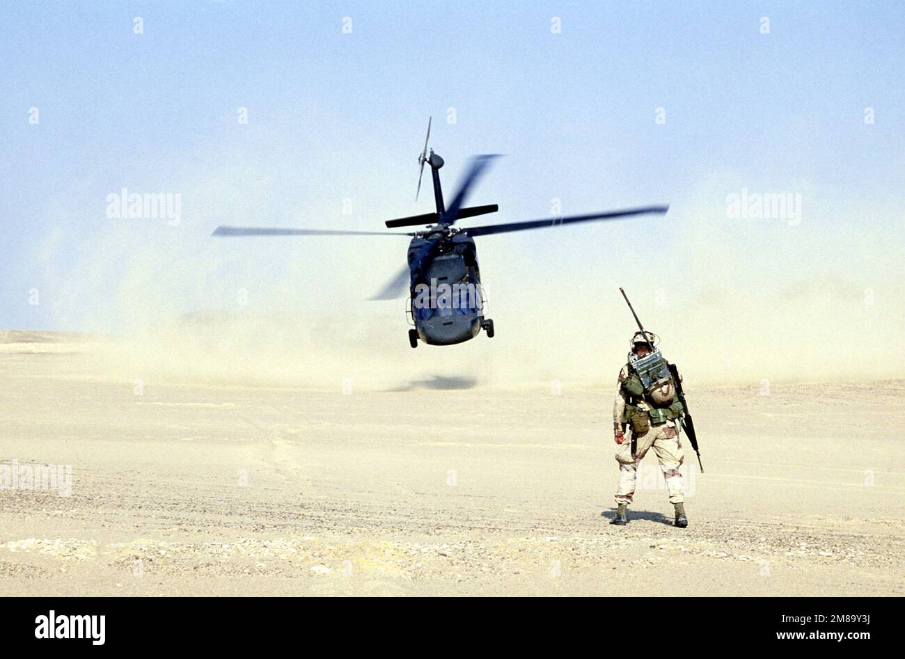 U.S. Army soldier assists an Army UH-60 helicopter crew as it lands on ...