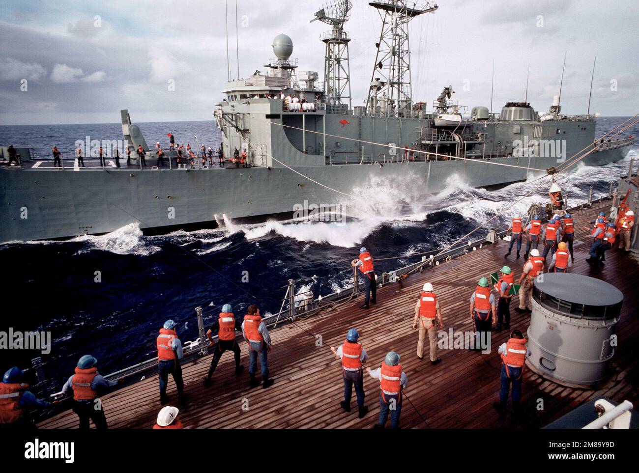 A crew member prepares to transfer by manila highline rig between the ...