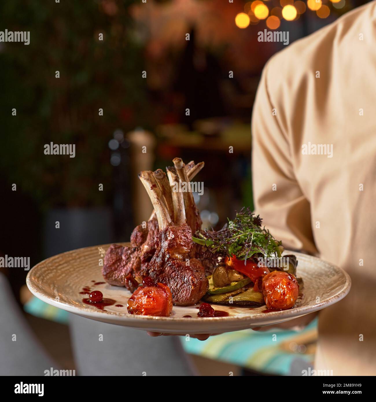 Hands holding cooked Tomahawk long bone ribeye steak on a serving board ...