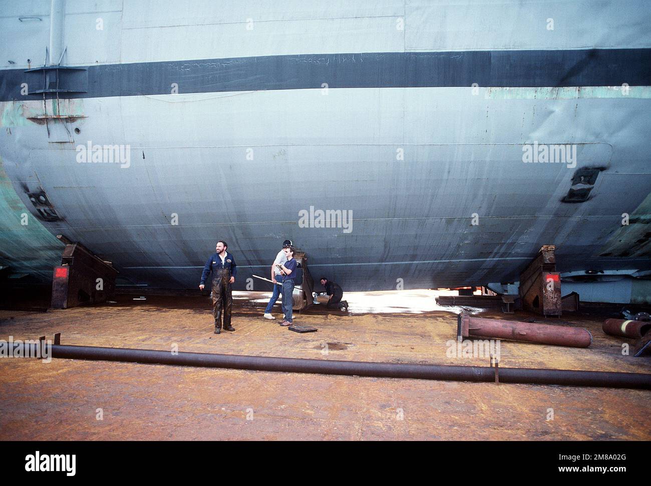 Yard workers repair the damage to the hull of the guided missile ...