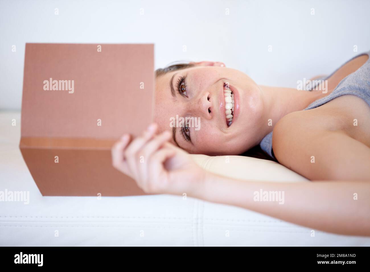 Chilling with a book. A young woman reading a book while lying on the ...