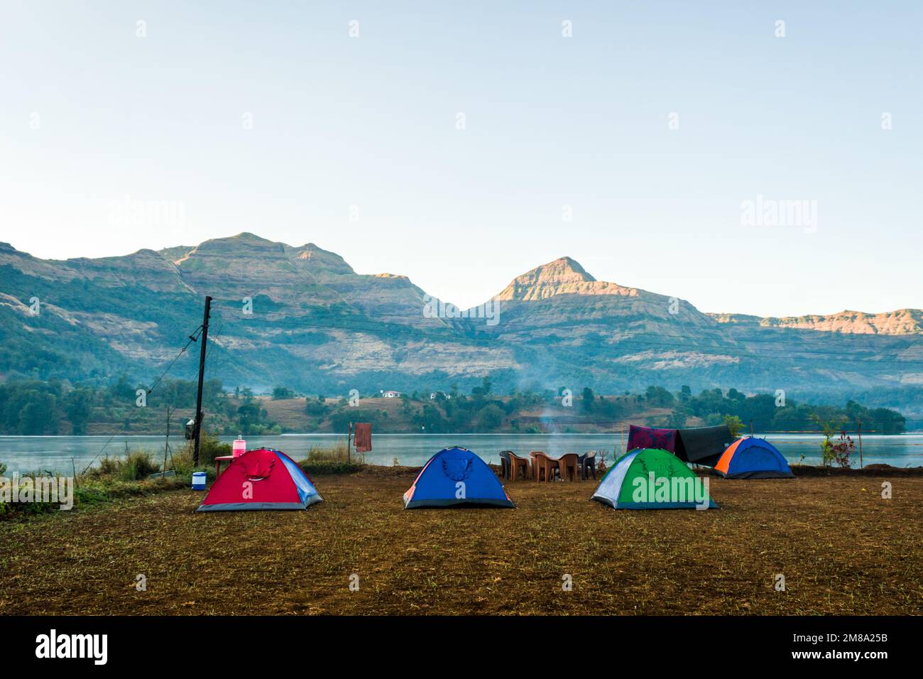 Beautiful landscape of camp and tents with hills in the background at Arthur Lake in Bhandardara ...