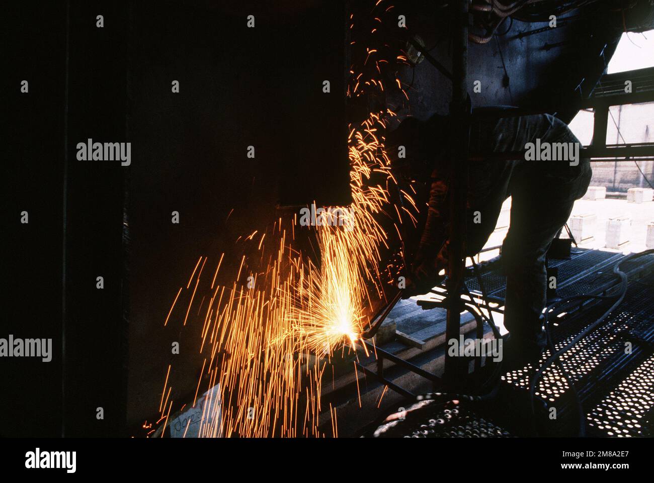 A shipyard worker welds a joint on the guided missile frigate USS ...