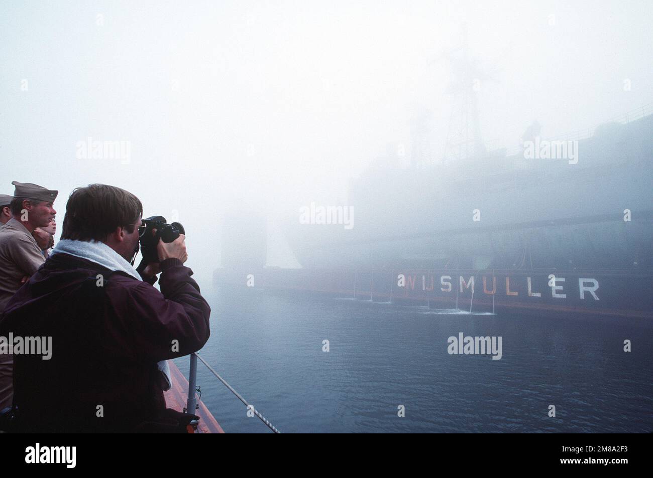 An off-duty sailor photographs the guided missile frigate USS SAMUEL B ...