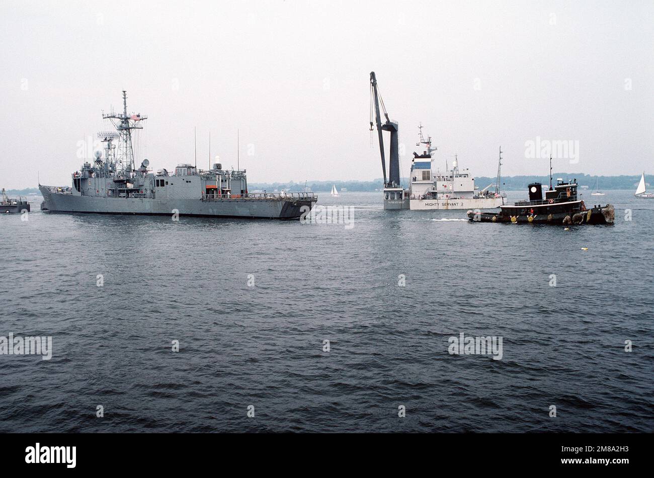 A tug boat tows the guided missile frigate USS SAMUEL B. ROBERTS (FFG ...
