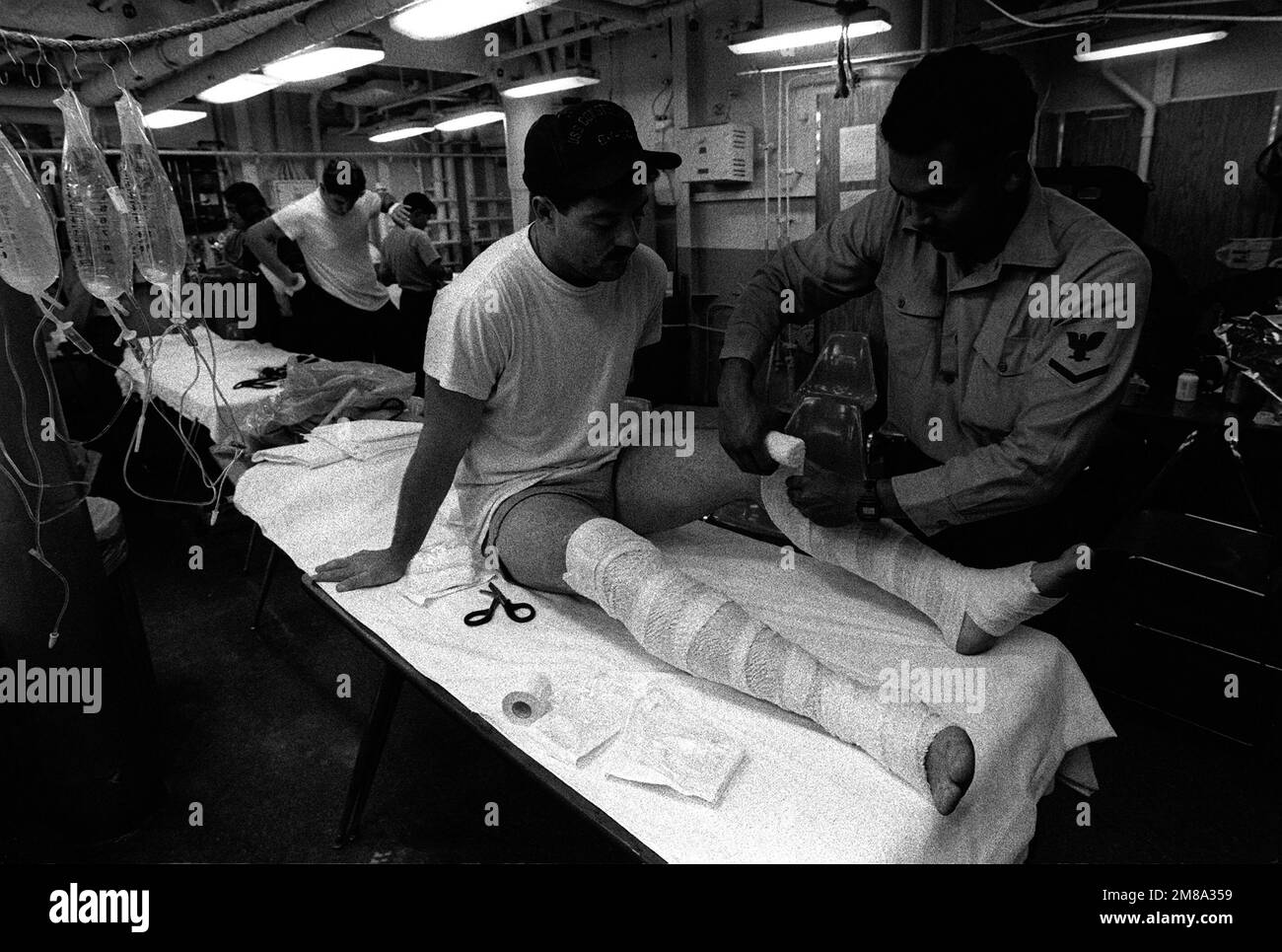 A corpsman wraps the legs of one of the crewmen injured during an ...