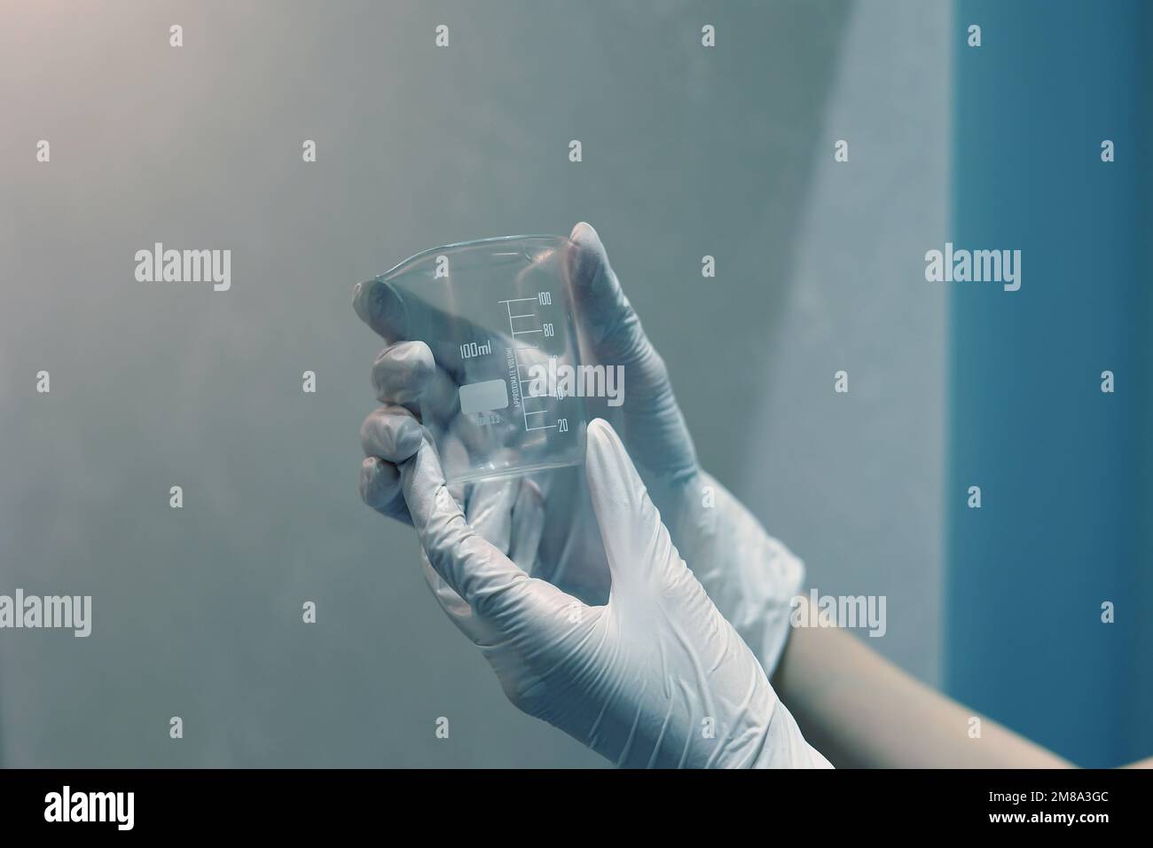 Gloved hands holding an empty beaker in the laboratory Stock Photo - Alamy