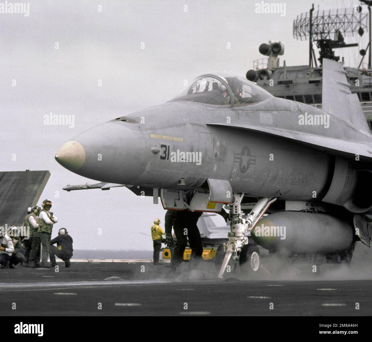 An F/A-18 Hornet aircraft is attached to a catapult on the flight deck ...