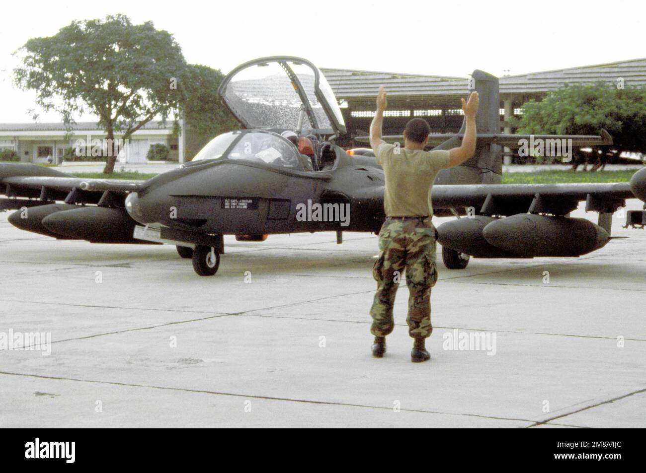 A ground crewman guides the pilot of an OA-37 Dragonfly aircraft. Base ...
