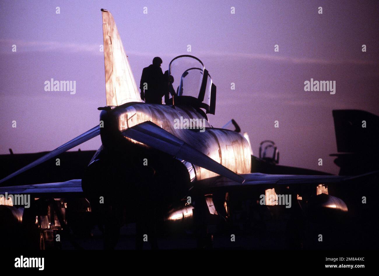 Ground crewmen are silhouetted against the late afternoon sky as they ...