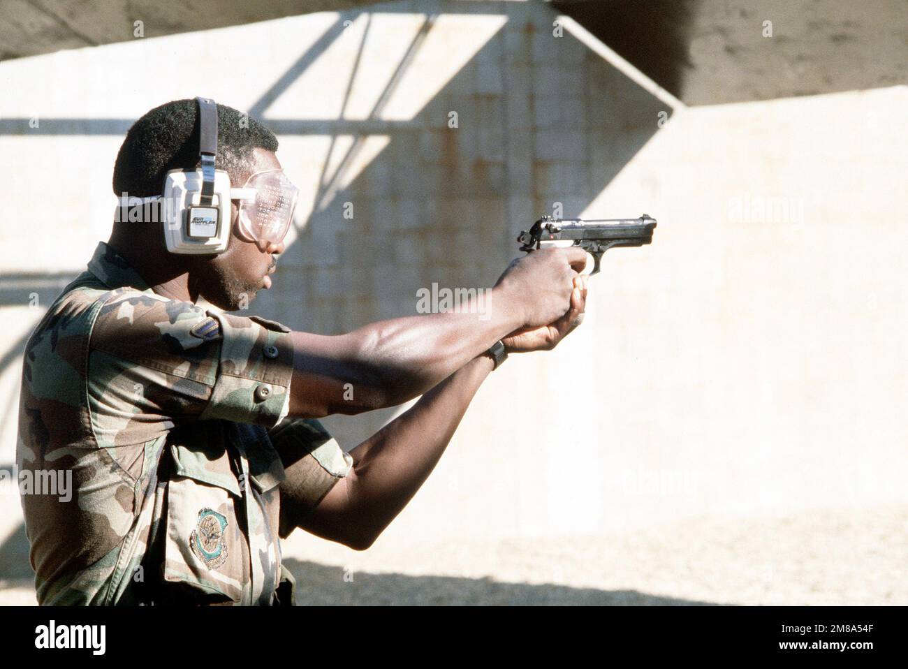 AIRMAN 1ST Class Eric Burks fires an M9 9 mm pistol on a target range ...