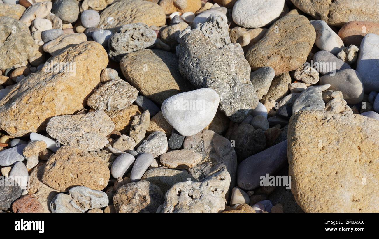 Cobble pieces of marble rock near water edge in Caesarea Maritima ...