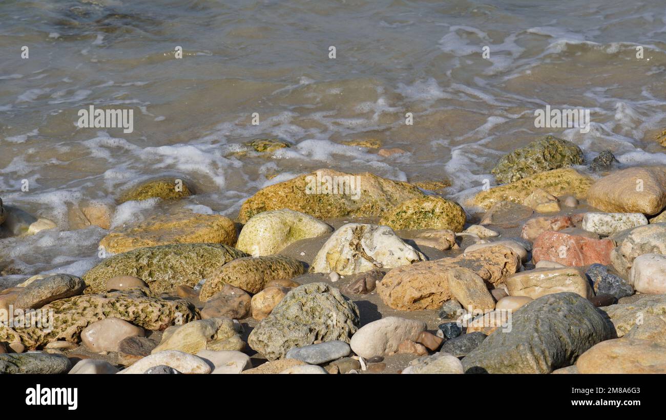 Cobble pieces of marble rock near water edge in Caesarea Maritima ...