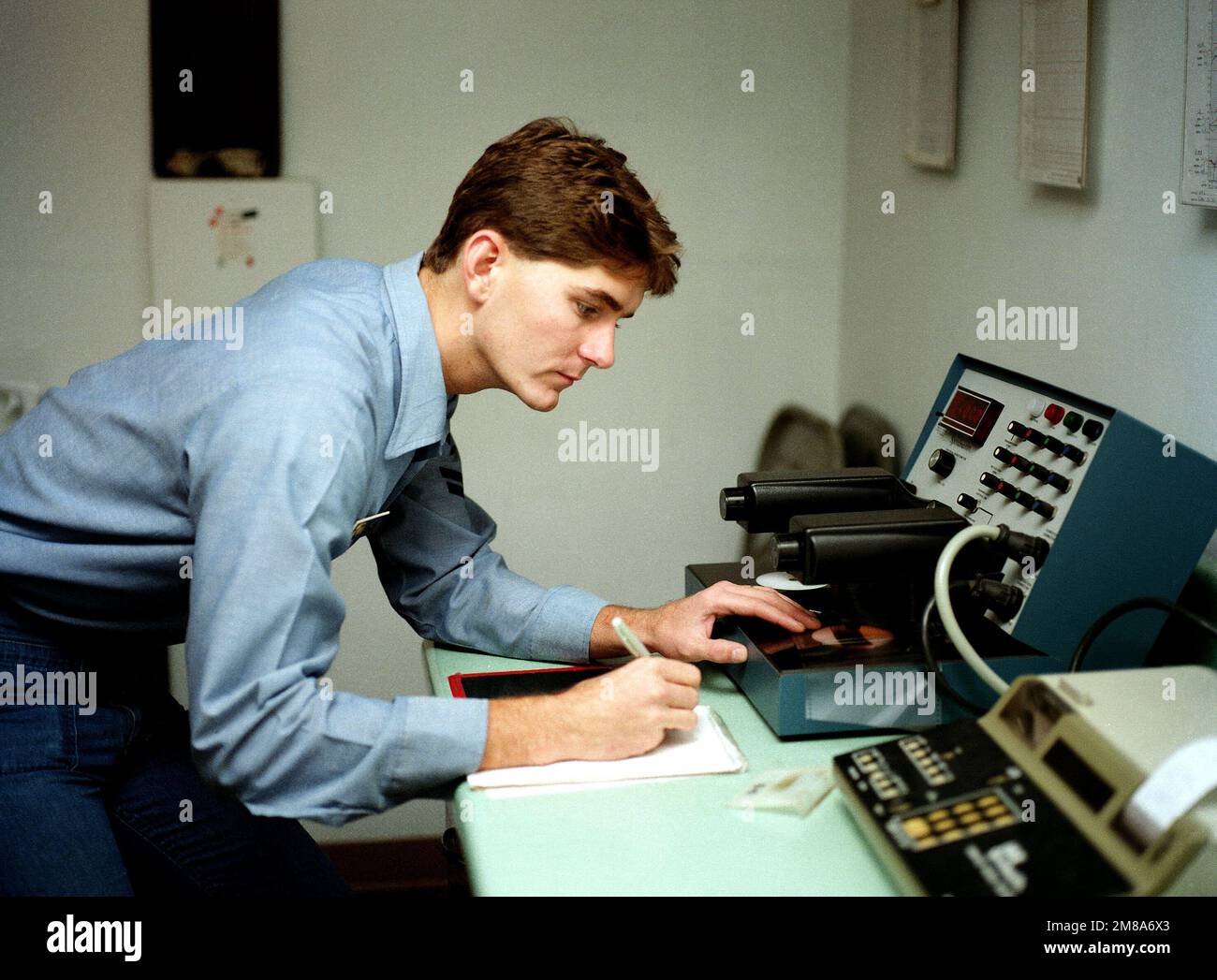A photographer's mate uses a densitometer to plot negatives at the ...
