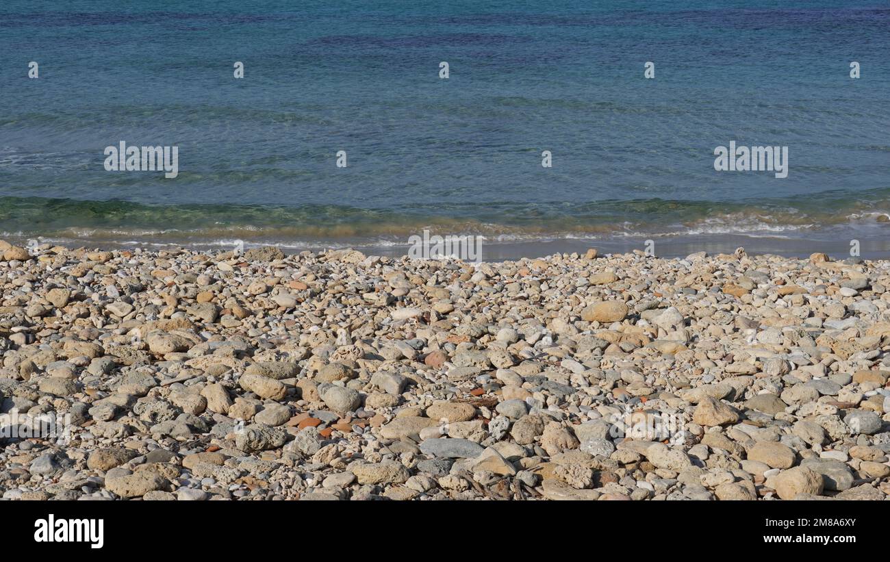 Cobble pieces of marble rock near water edge in Caesarea Maritima ...
