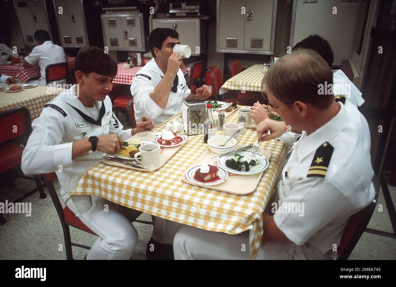 An officer and three enlisted men share a table on the mess deck of the ...